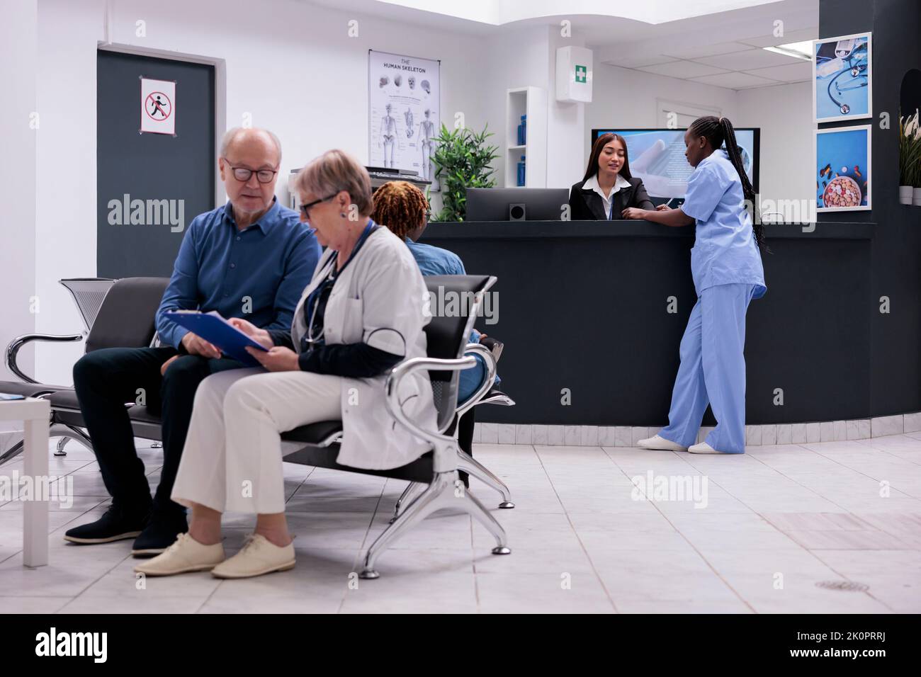 Diverse medical team working at reception desk, filling in checkup ...