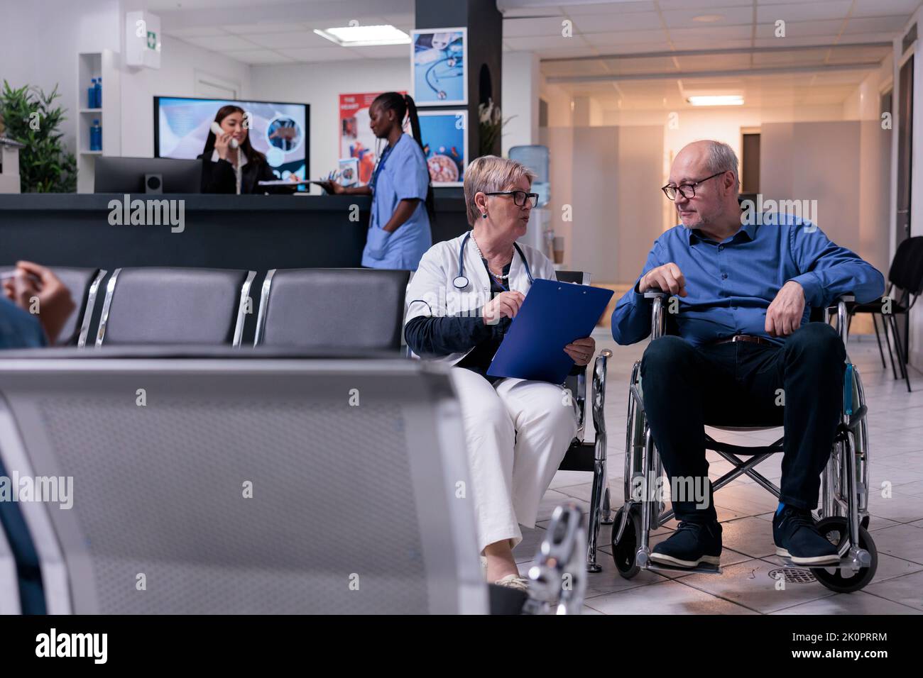 Old doctor consulting man with disability in waiting room lobby, doing ...