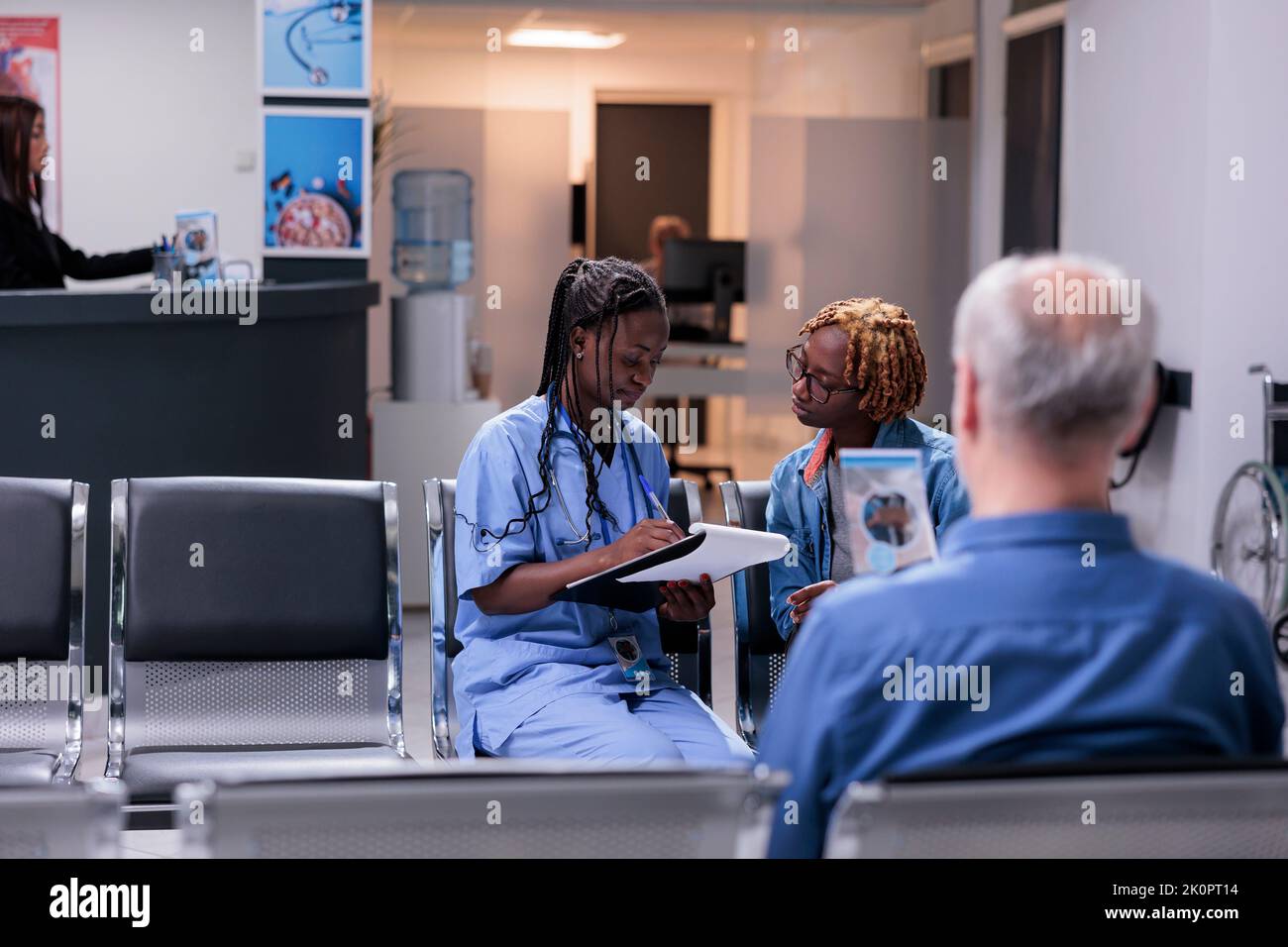 Female nurse taking notes at examination appointment with young patient ...