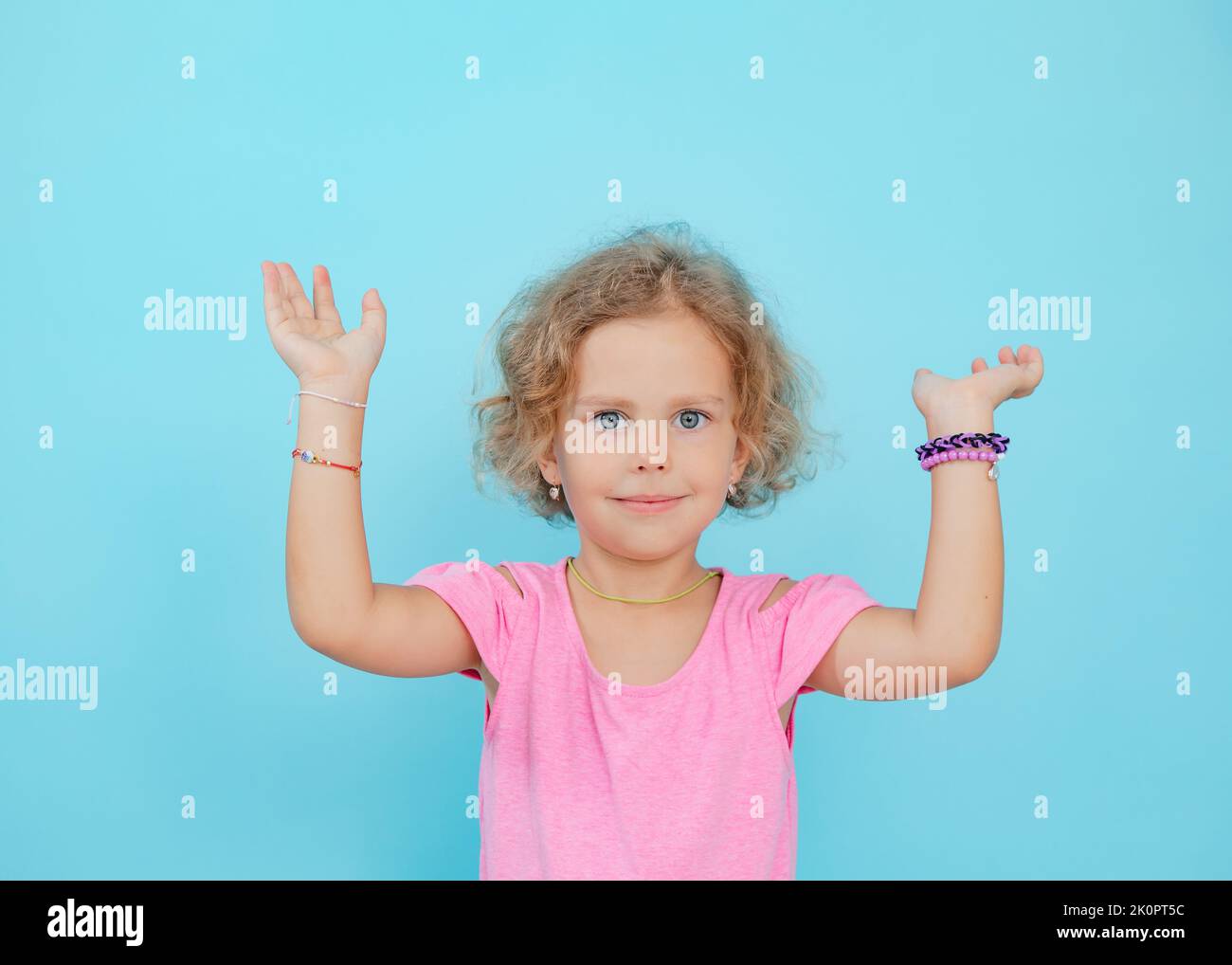 Beautiful little girl show handmade bead jewelery on empty blue ...