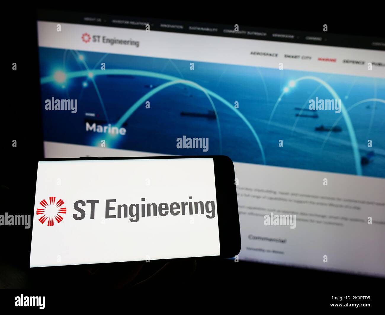 Person holding cellphone with logo of Singapore Technologies Engineering Ltd. (ST) on screen in ...