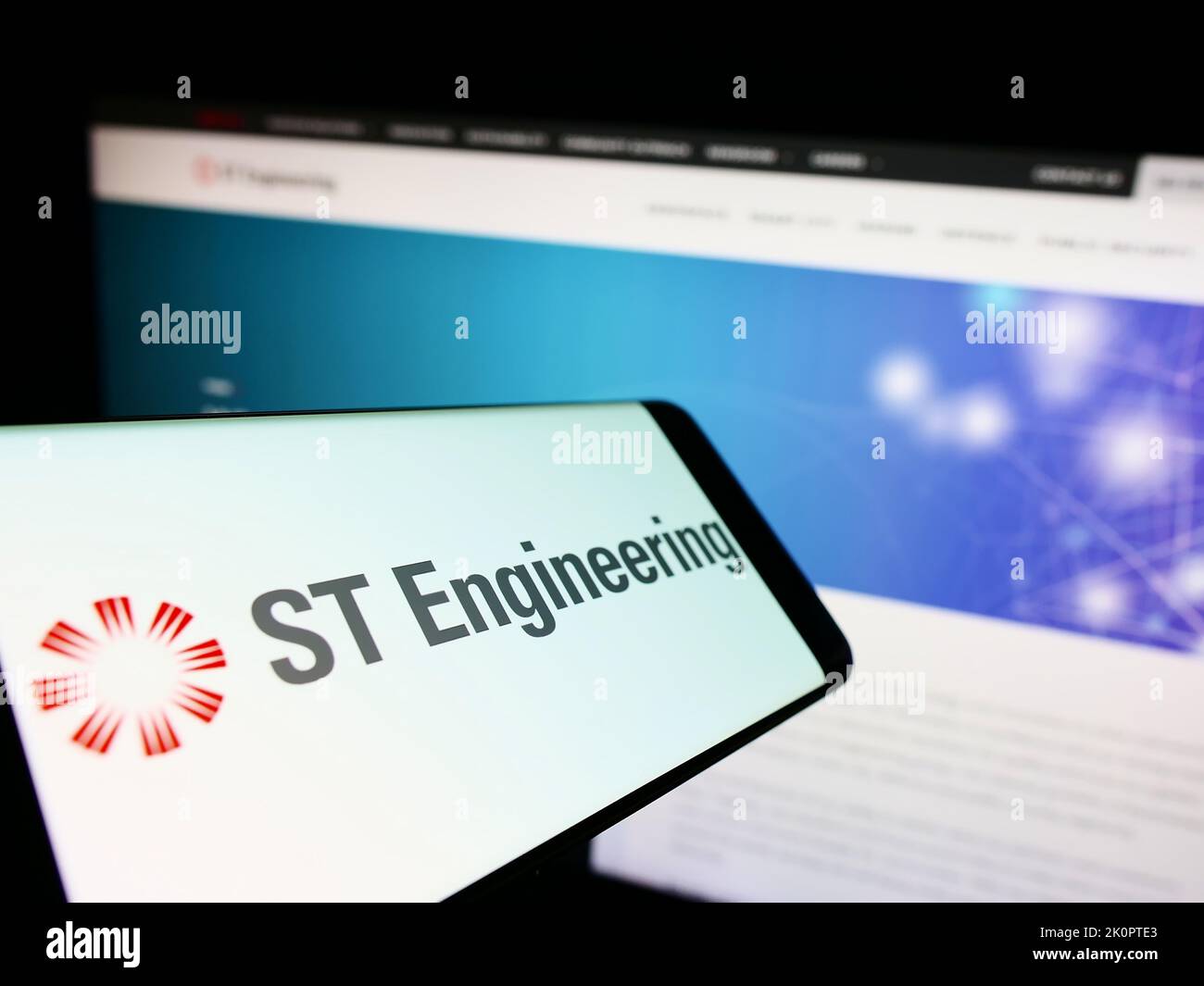 Cellphone with logo of Singapore Technologies Engineering Ltd. (ST) on screen in front of ...
