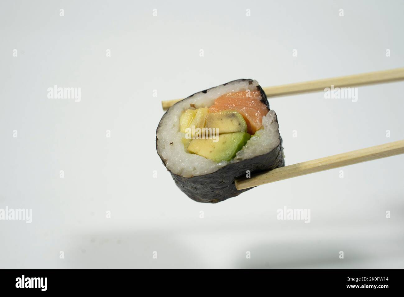 a piece of shushi with chopsticks in white background Stock Photo - Alamy