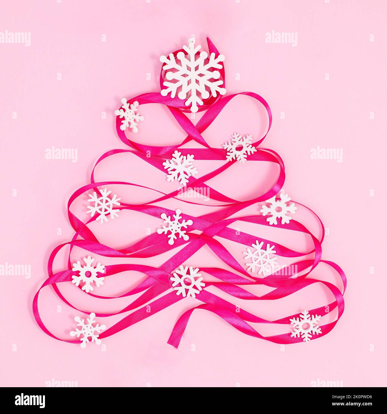 Creative Chrismtas tree shape with pink ribbon and snowflakes on pastel ...
