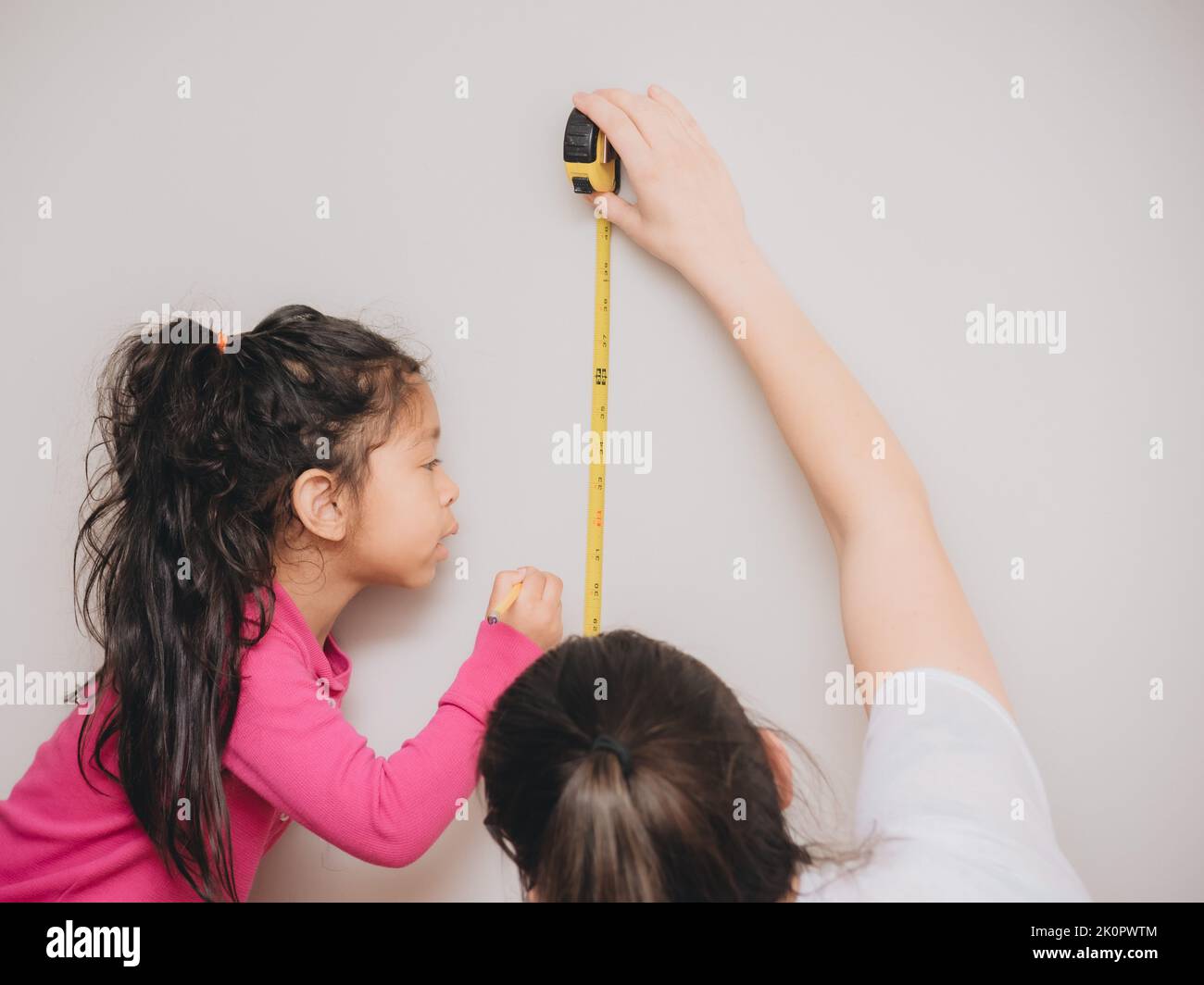 young millennial mother at home using measuring tape to measure her ...