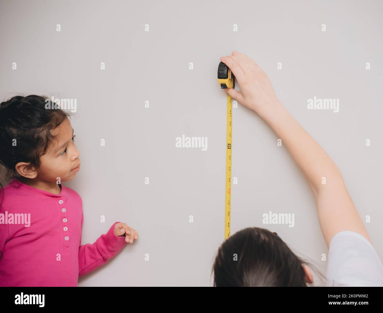 young millennial mother at home using measuring tape to measure her ...