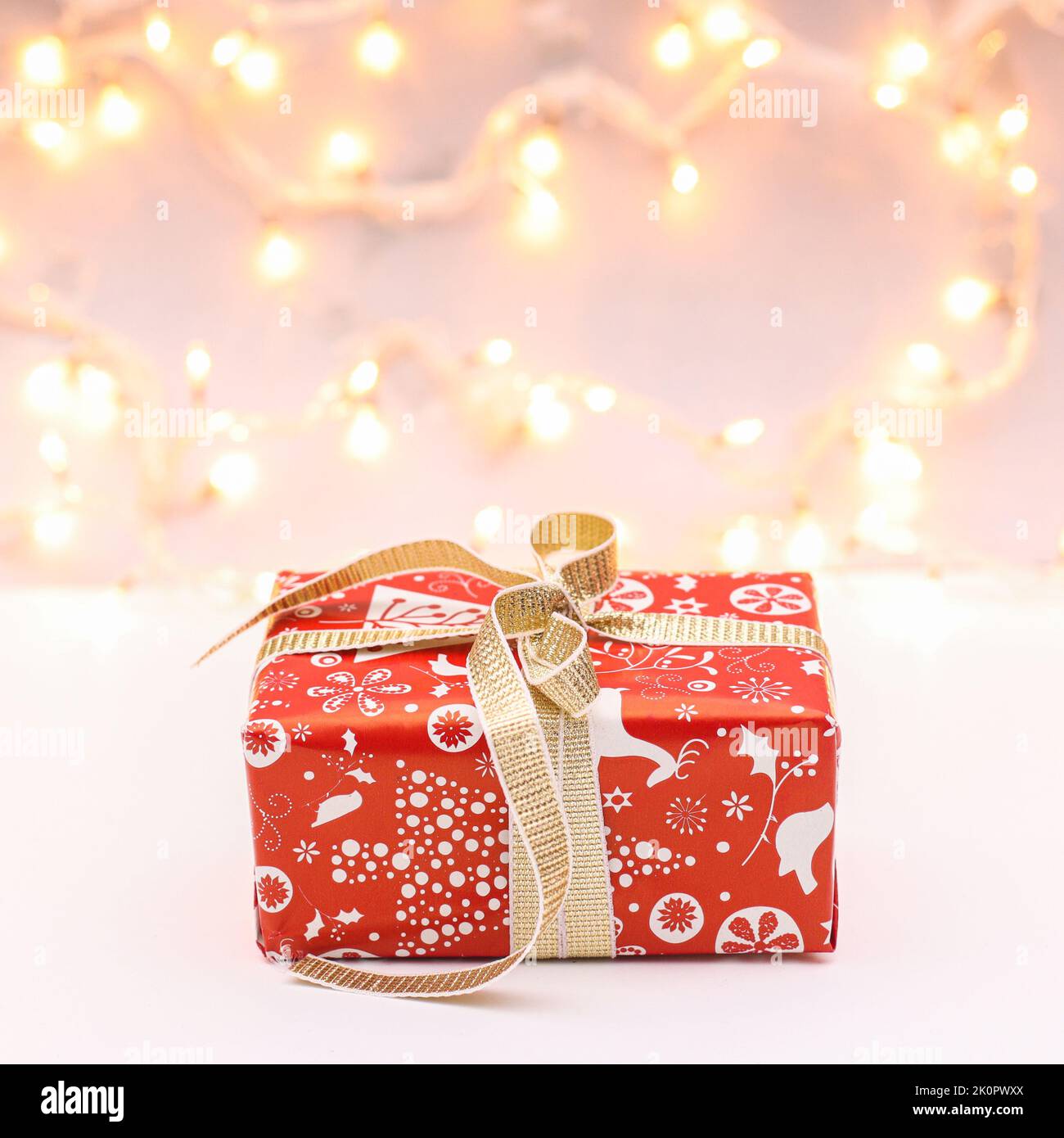 Red Christmas gift with golden ribbon with lights on background. New ...