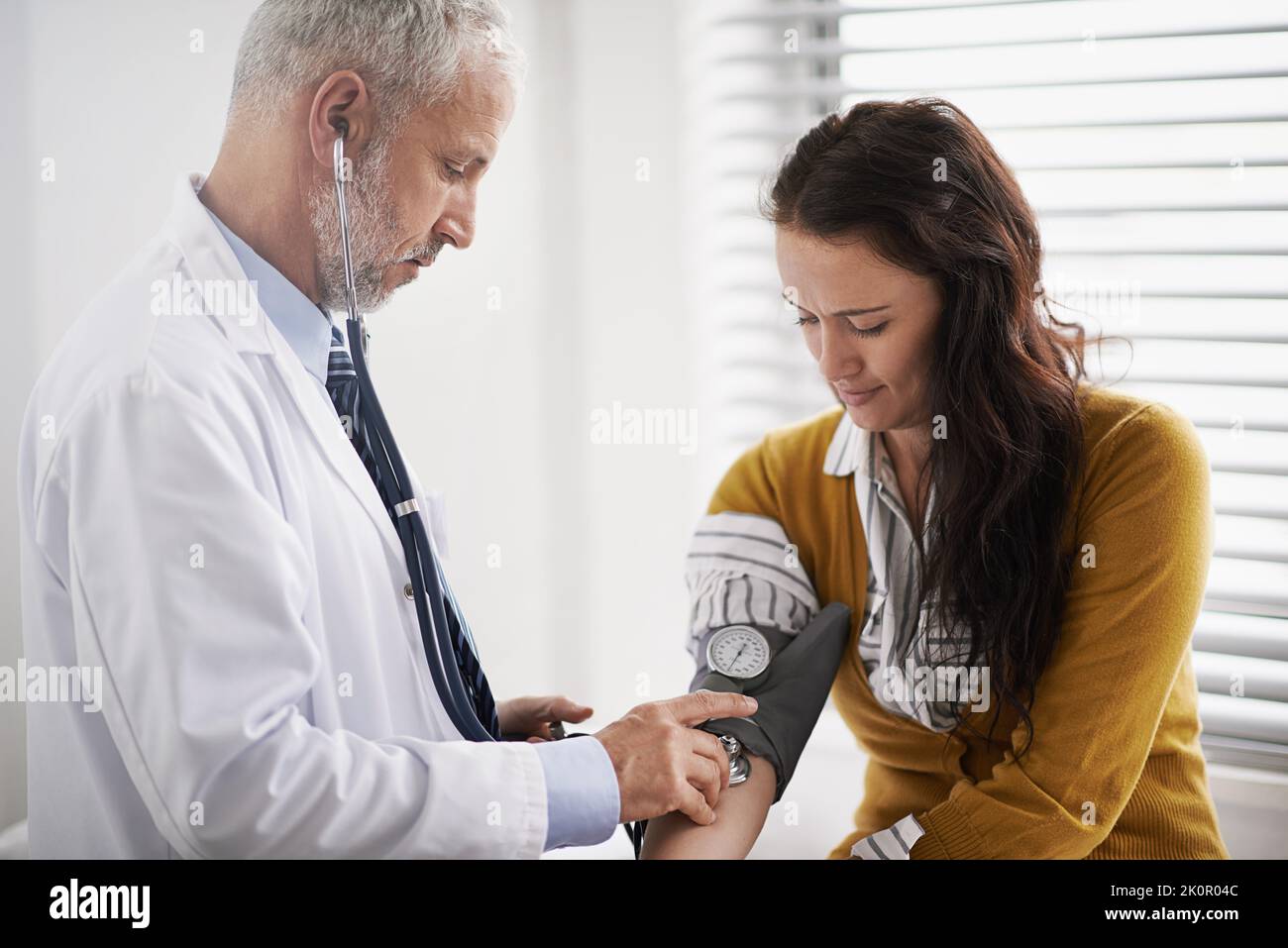 Getting her annual checkup. a doctor checking a patients blood pressure ...