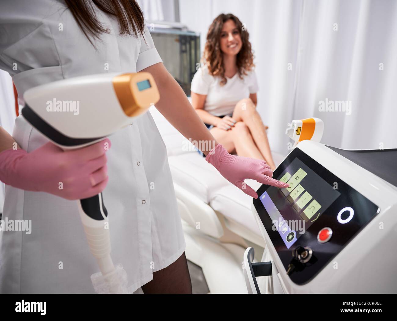 Close up of female beautician in sterile gloves using diode laser hair removal machine while ...