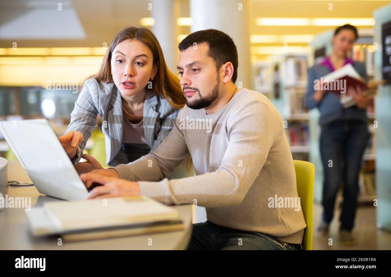 Positive adults communicating while preparing to exam in library Stock ...