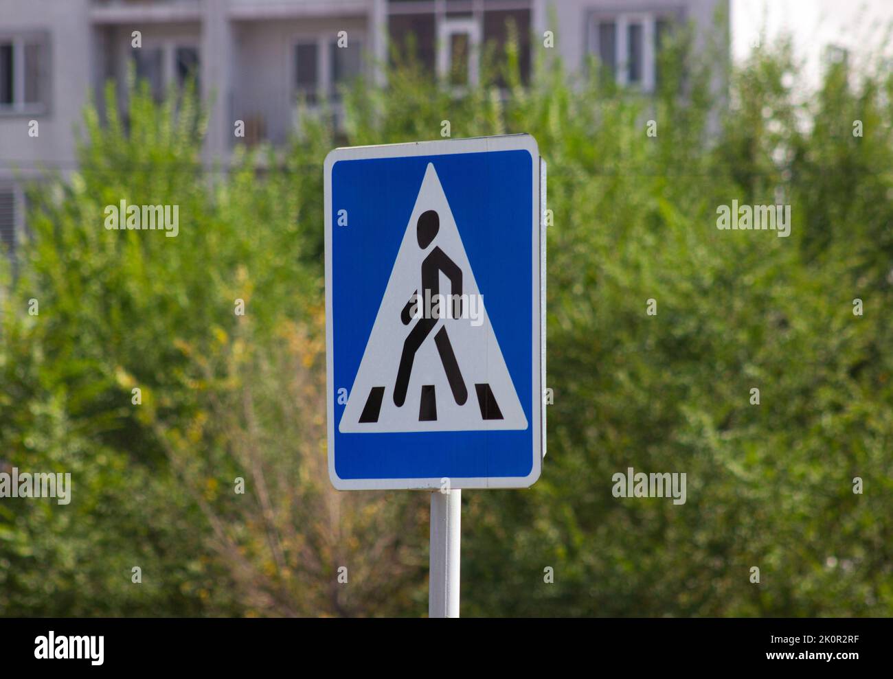 Pedestrian triangle road sign blue background Stock Photo - Alamy