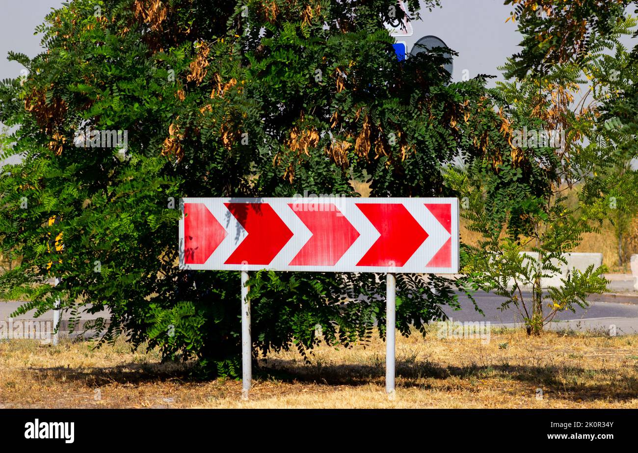 Turn road traffic direction white arrows red background sign in front ...