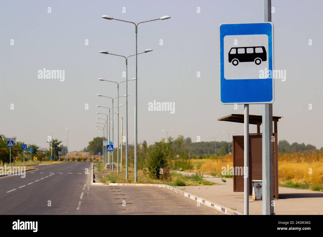 Bus stop sign on the blue background near bus station Stock Photo - Alamy
