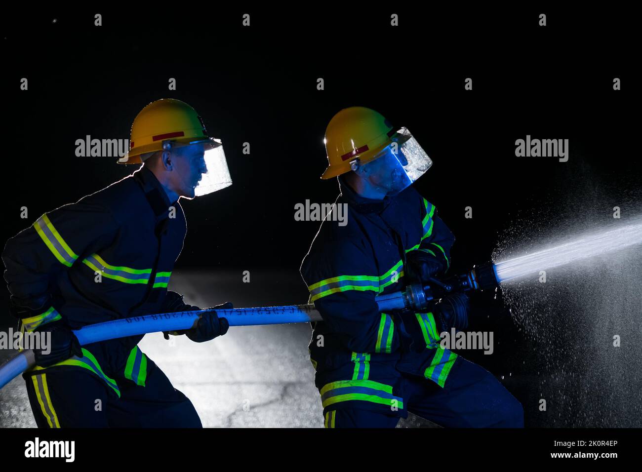 Firefighters use a water hose to eliminate a fire hazard. Team of ...
