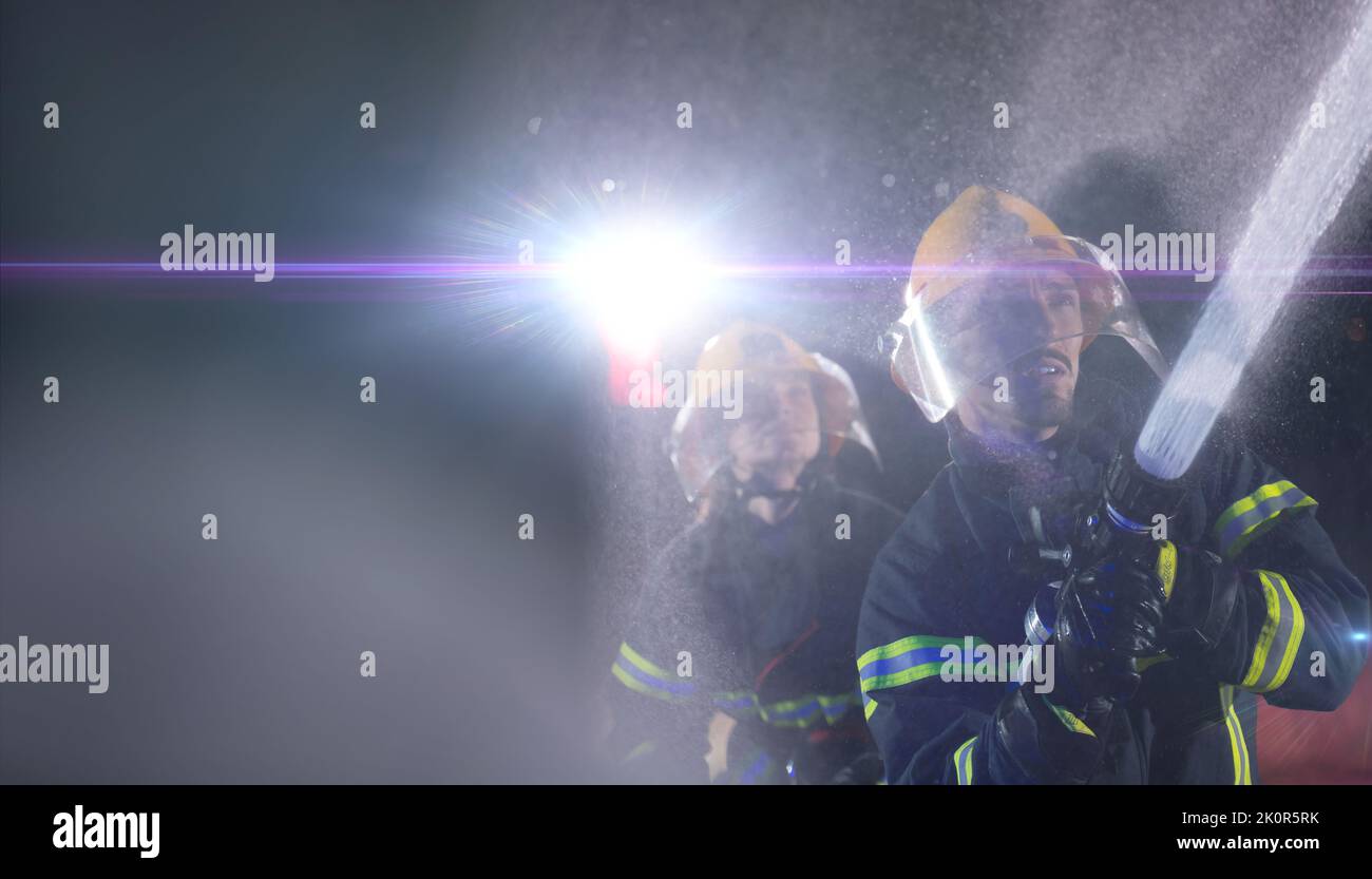 Firefighters using a water hose to eliminate a fire hazard. Team of ...