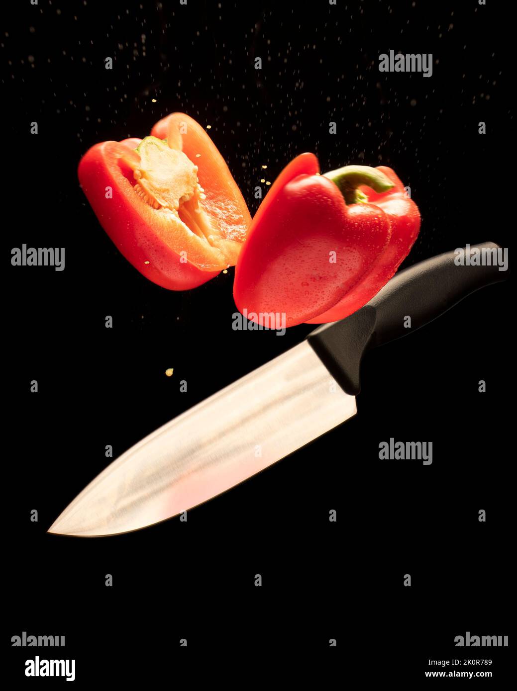 A vertical shot of halved red pepper and sharp knife floating in the ...