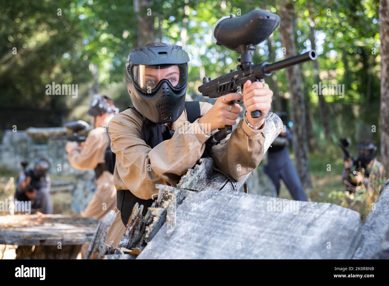 Young woman paintball player shooting with paintball marker Stock Photo ...