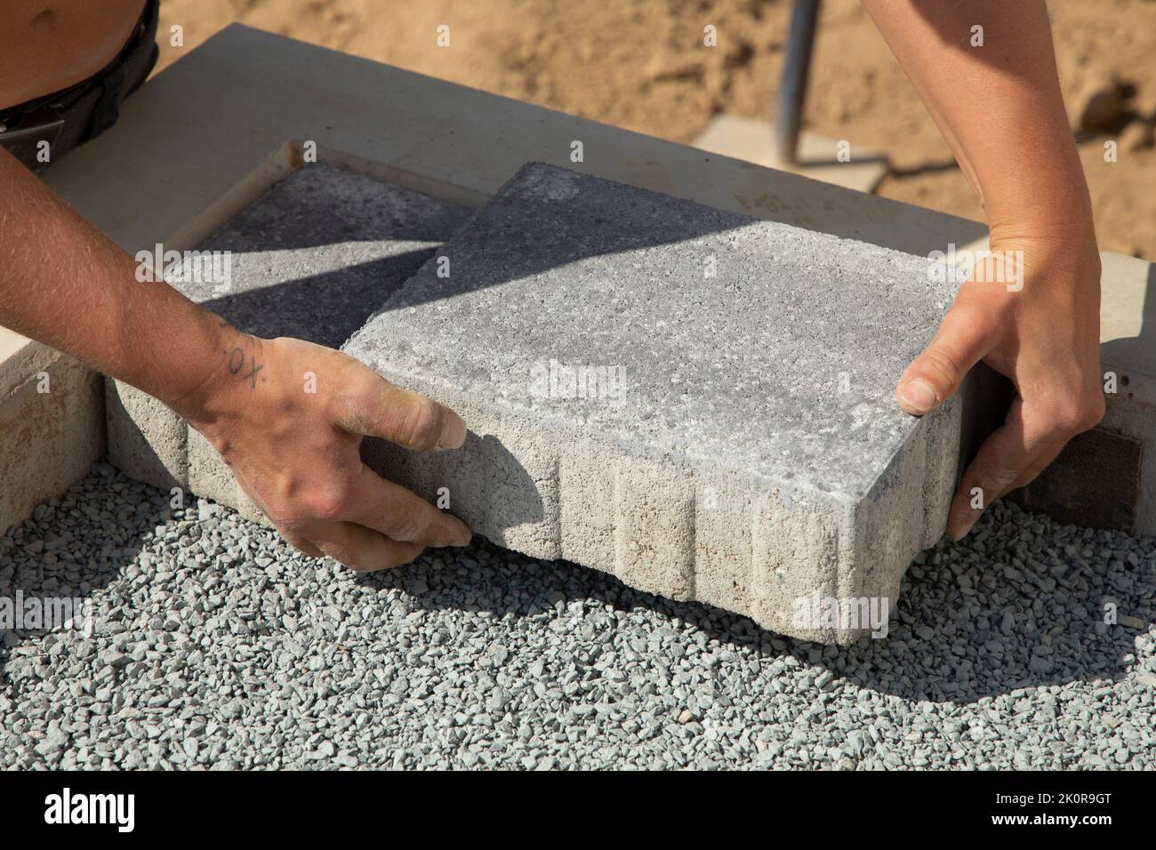 craftsman lays down the paving stones in layers. Laying gray concrete ...