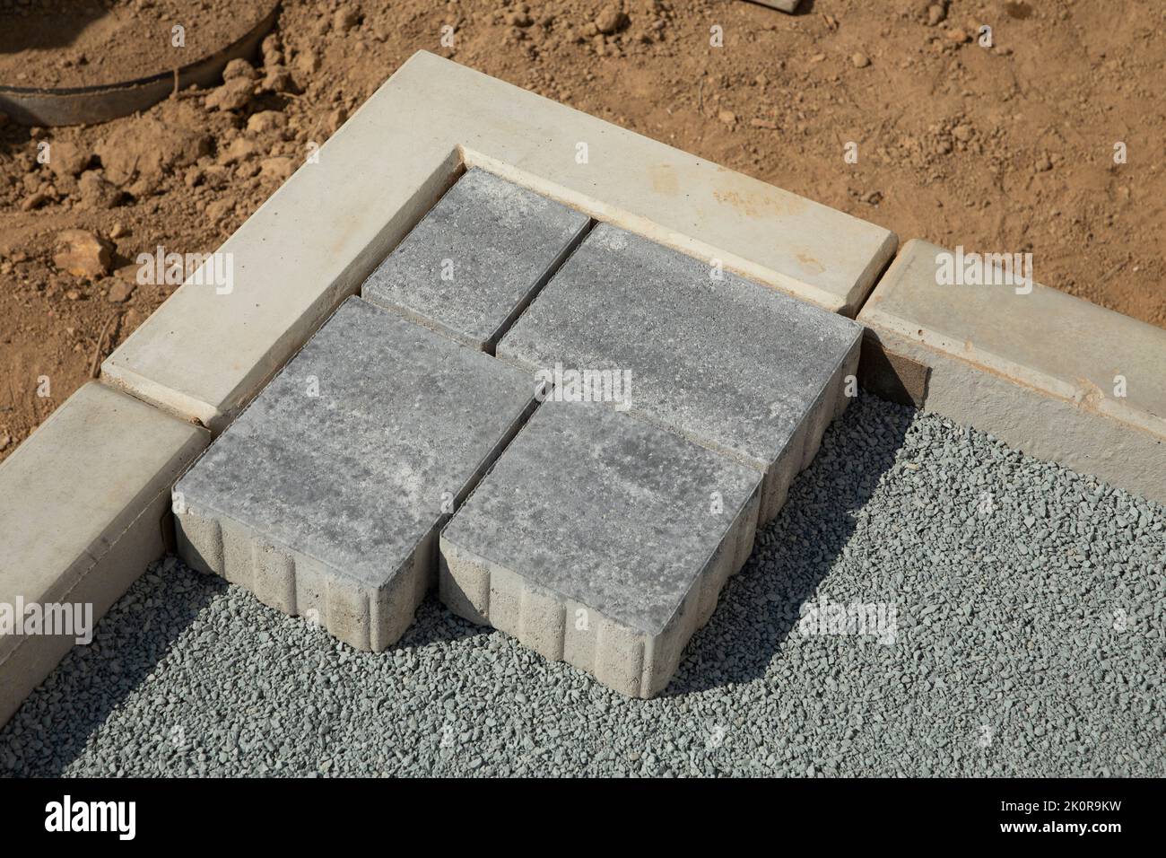A gloved craftsman lays down the paving stones in layers. Laying gray ...
