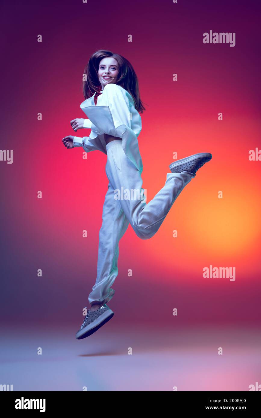 Portrait of young beautiful woman posing in a jump isolated over red ...