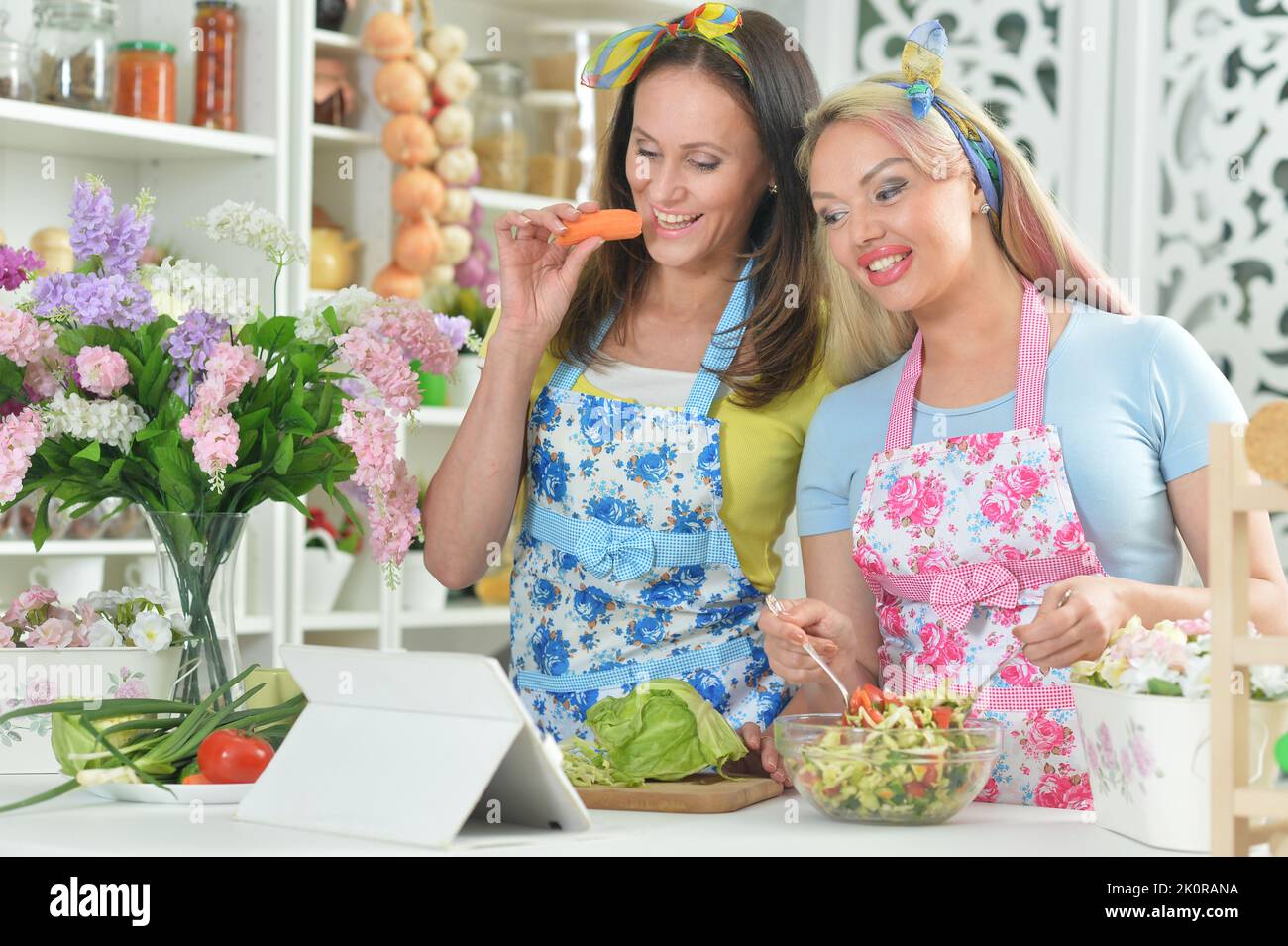 Two beautiful young women cooking together in kitchen Stock Photo - Alamy