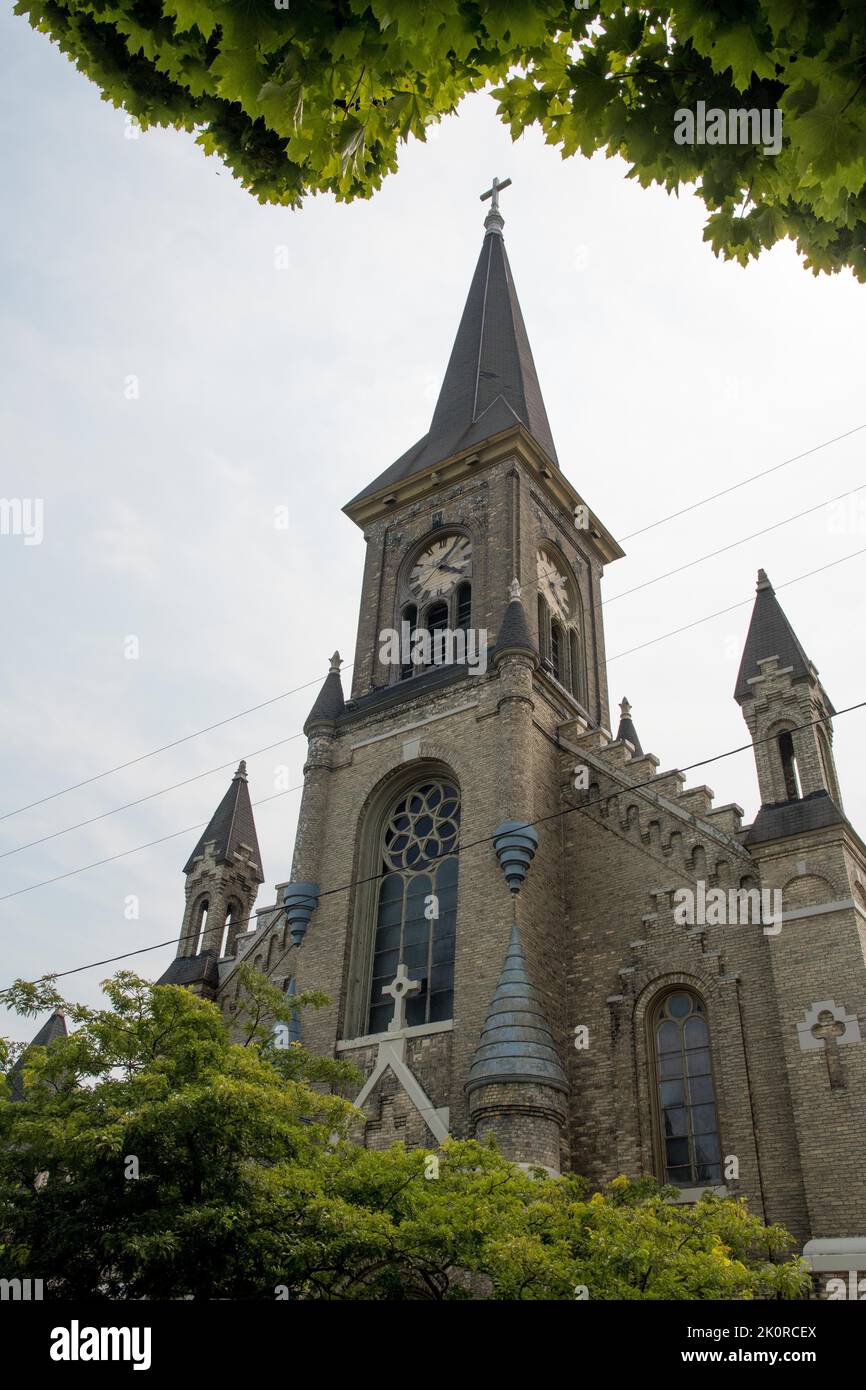 A low-angle shot of Sacred Heart church in Michigan with trees and sky ...