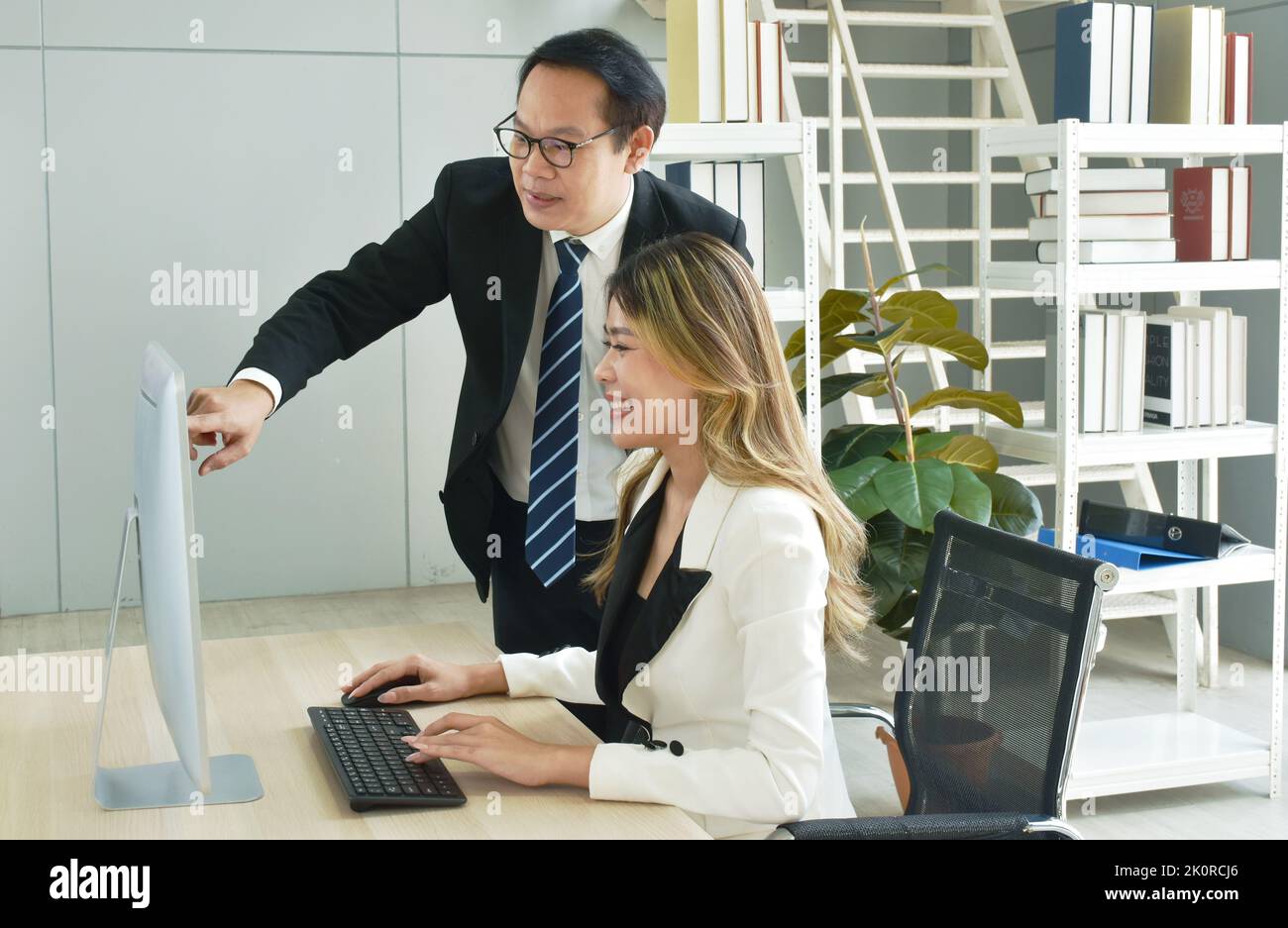 Asian business man and woman looking at computer laptop screen to ...