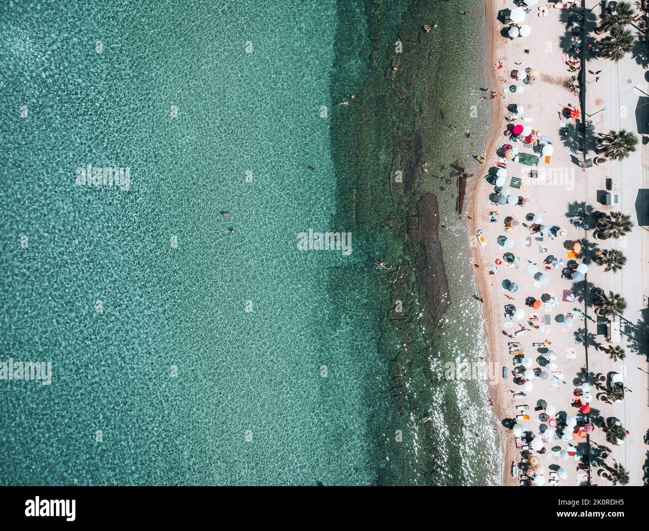 An aerial top shot of a sandy beach with people and sea waves ...