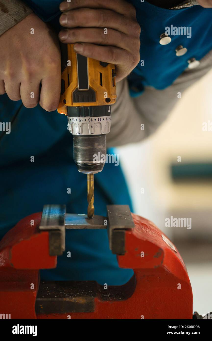 Technician worker hands making a hole in a piece of metal using drill ...