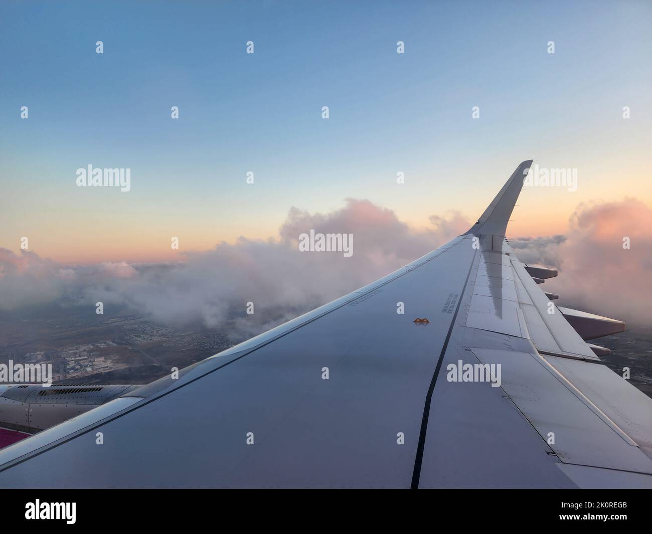 A wing of an airplane captured at sunset during the flight Stock Photo ...