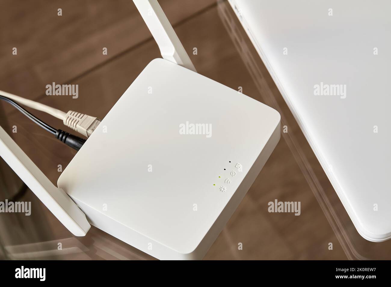 White wireless wi-fi router near a laptop on a glass table Stock Photo ...
