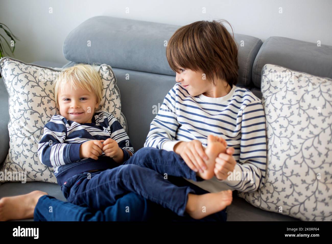 Little toddler and his older brother, having fun at home, tickling and ...