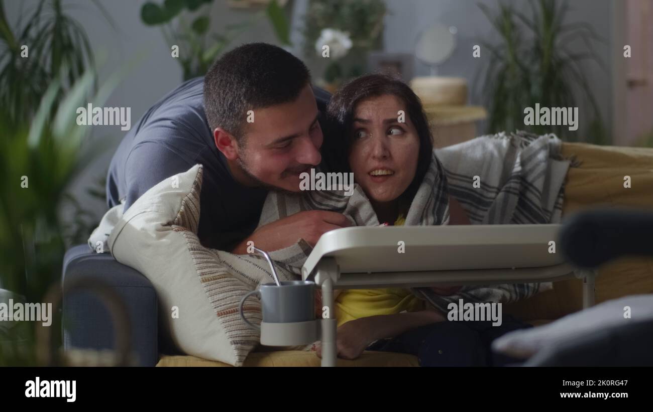 Husband covering his wife with disability with blanket while she ...