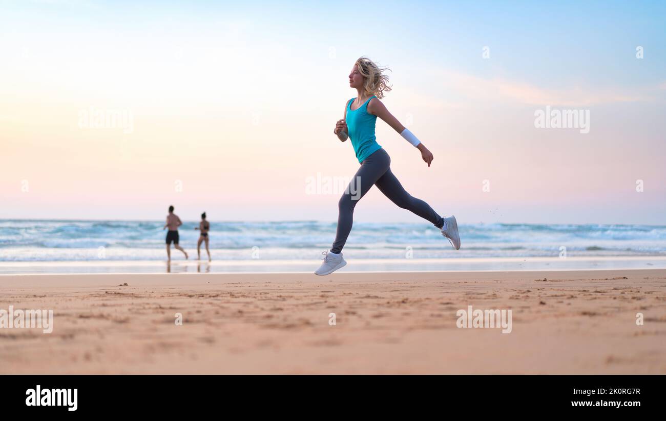 Active sporty woman run along ocean surf by water pool to keep fit and ...