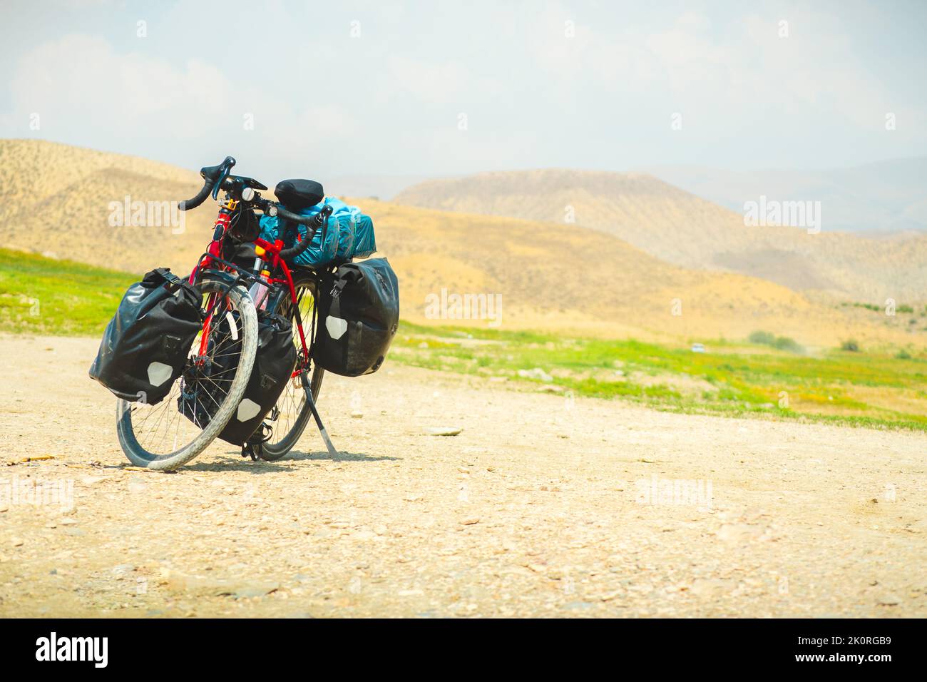 Loaded touring bicycle stands with moody dramatic panoramic mountains ...