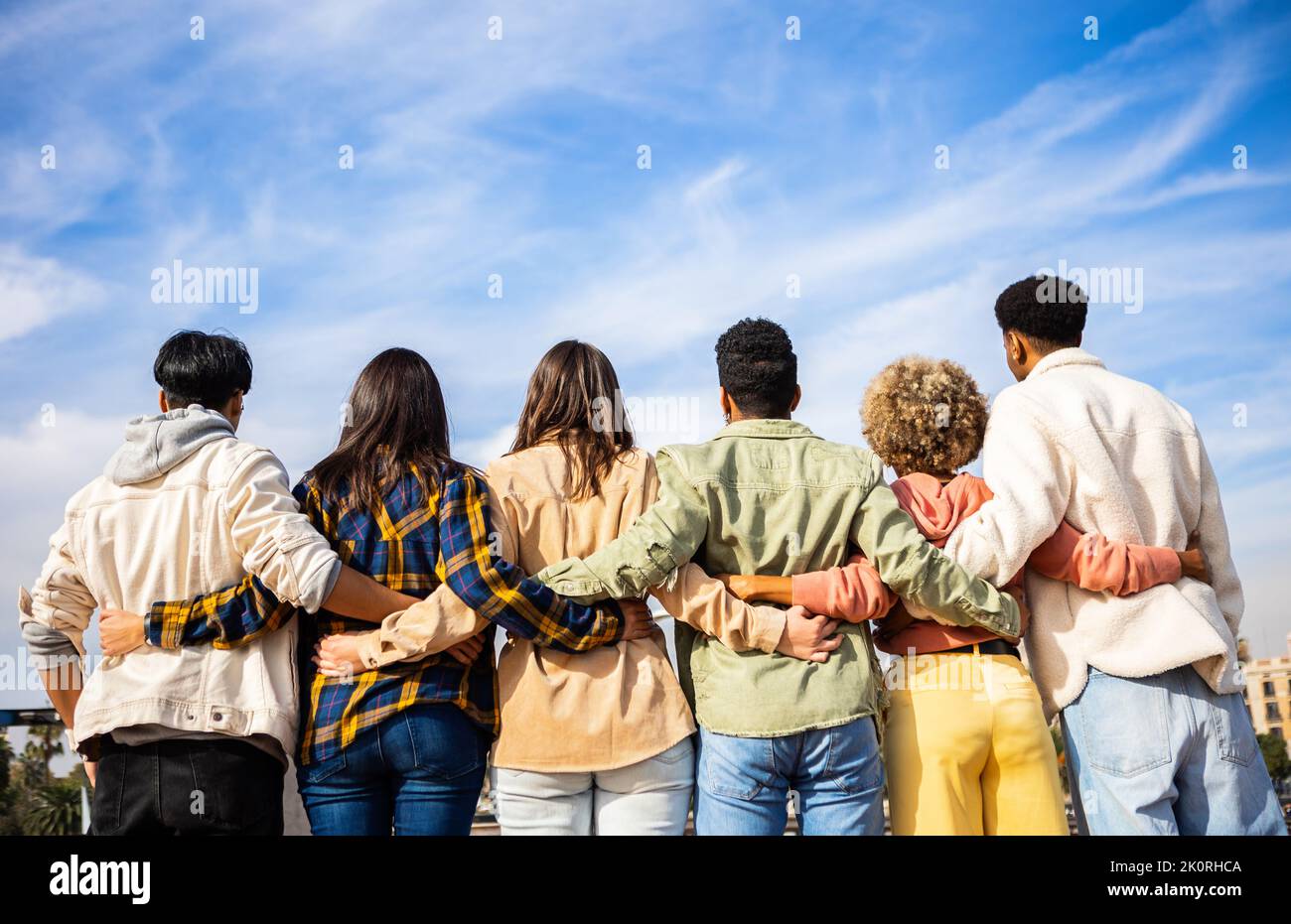 United group of young friends hugging each other standing in a row ...