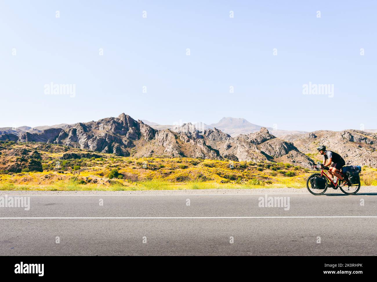 Aerial view caucasian male person solo cycle bicycle touring in countryside fully loaded with ...