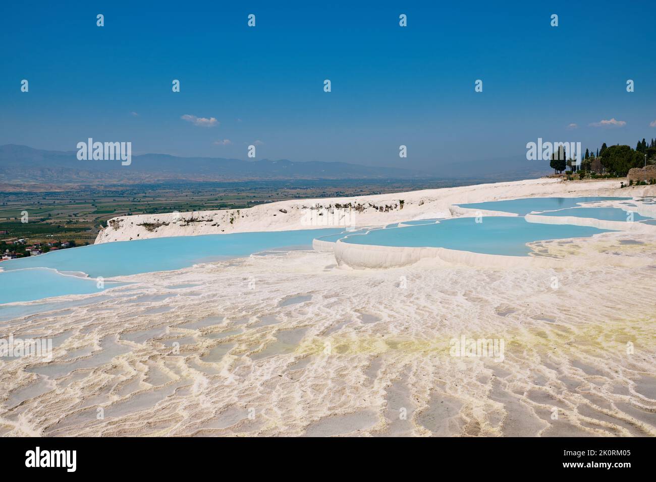blue pools with water and white travertine terraces of Pamukkale ...