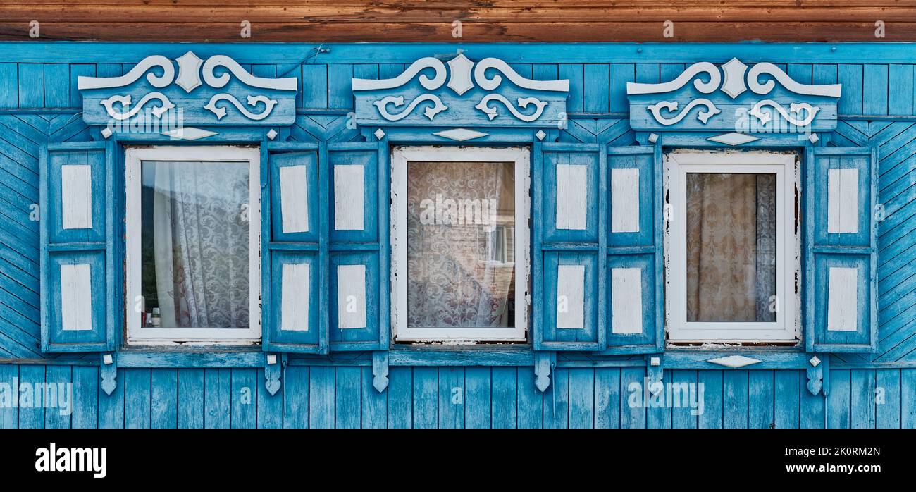 Old wooden blue windows with carved architraves and shutters on plank ...
