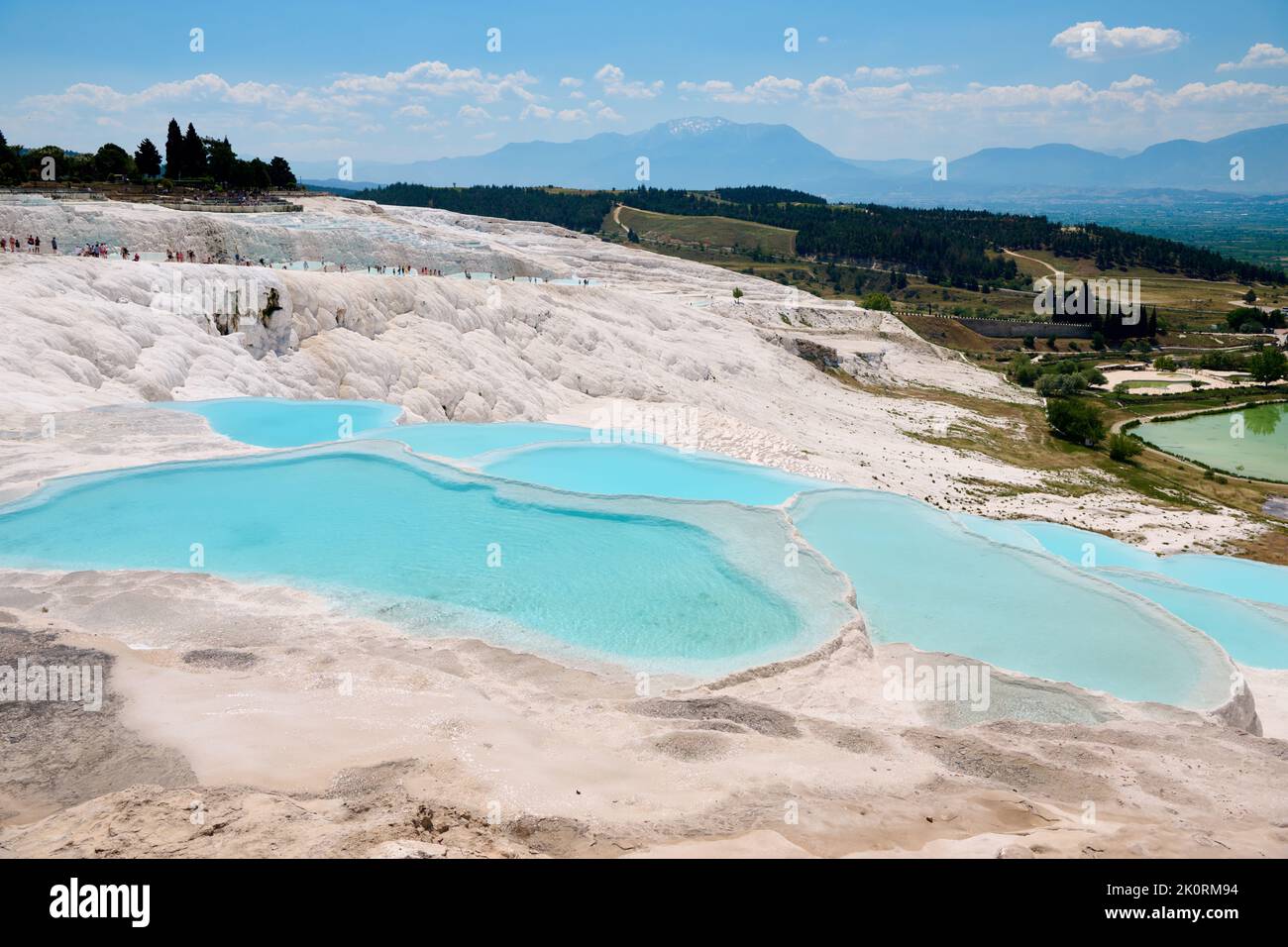 blue pools with water and white travertine terraces of Pamukkale ...