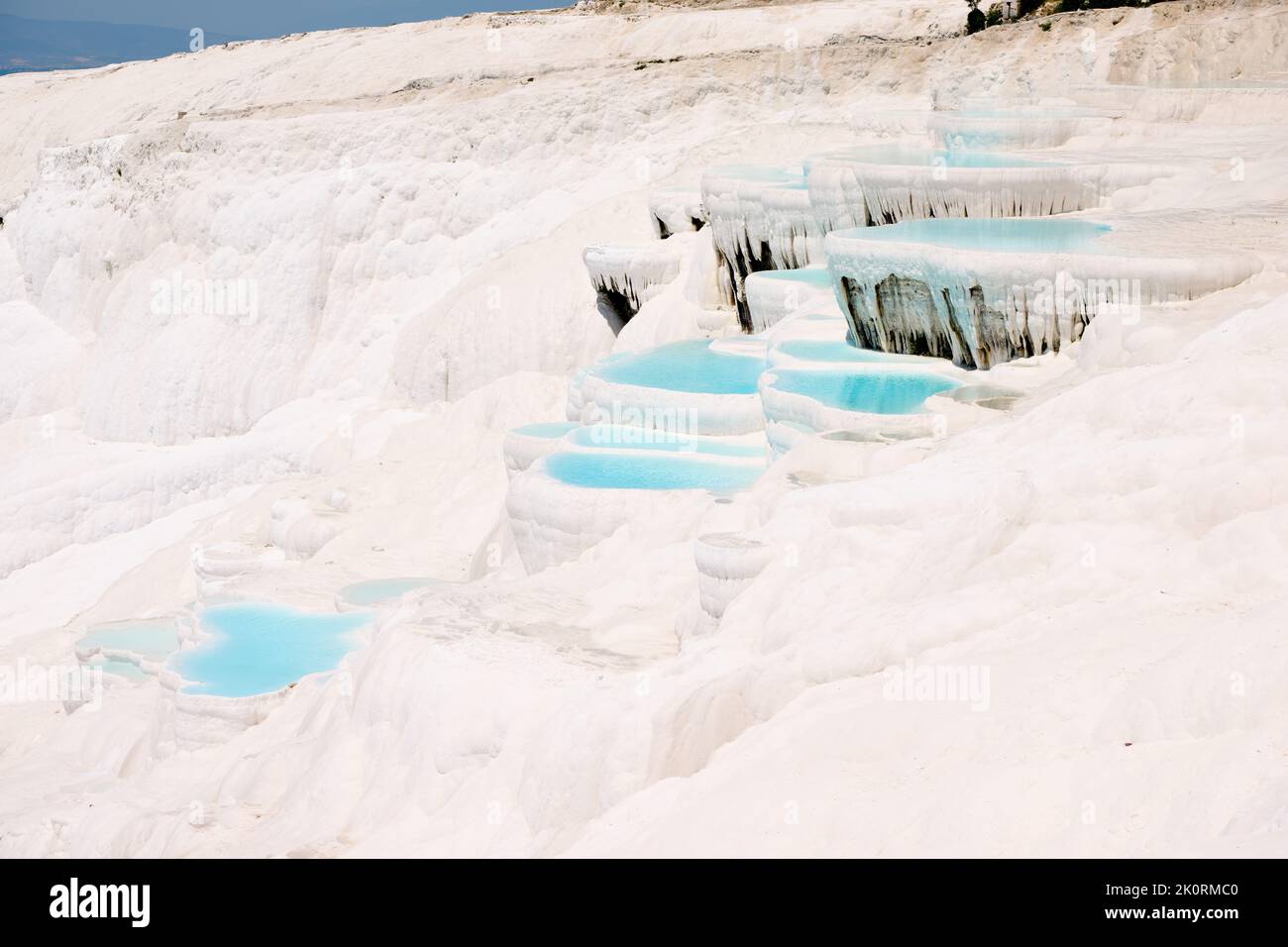 blue pools with water and white travertine terraces of Pamukkale ...