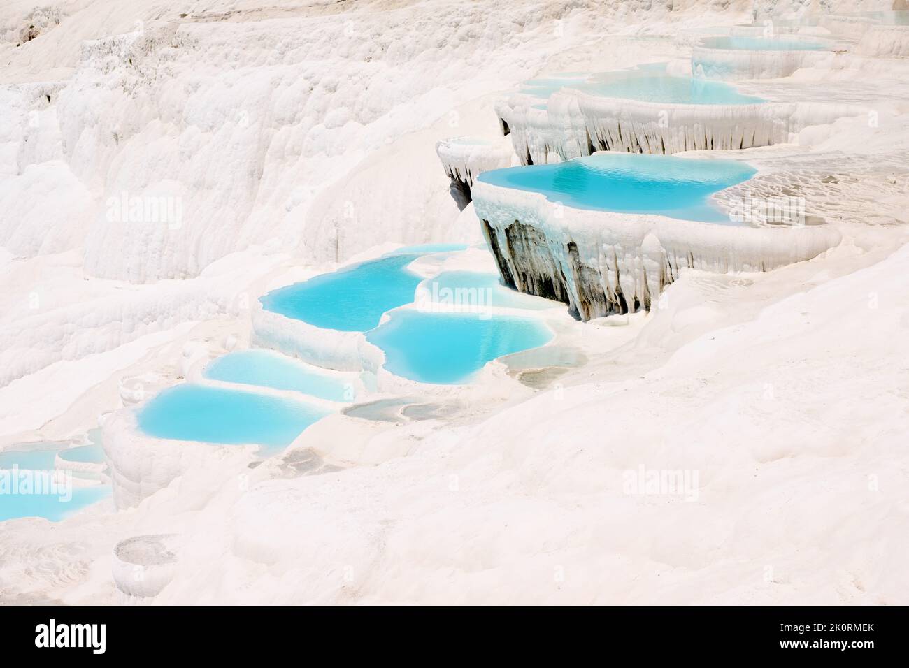 blue pools with water and white travertine terraces of Pamukkale ...