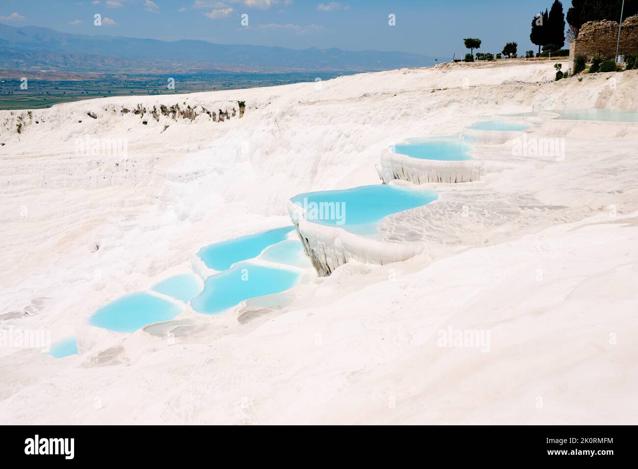blue pools with water and white travertine terraces of Pamukkale ...