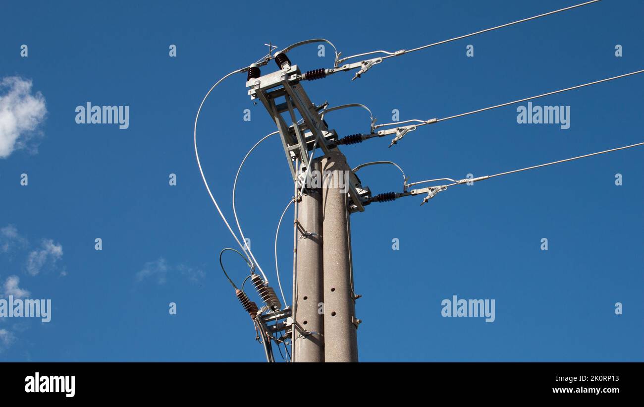 An electric cable wire on a post with a cloudy blue sky background ...