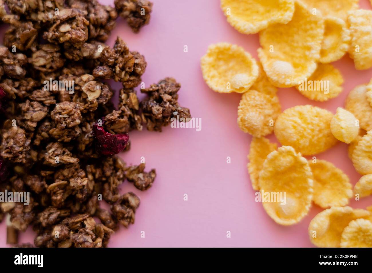 top view of crispy corn flakes and crunchy granola isolated on pink ...