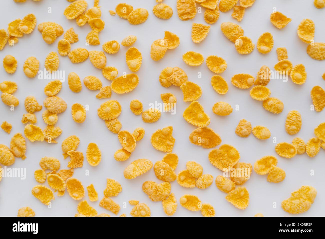 top view of crispy and yellow corn flakes on white background,stock ...