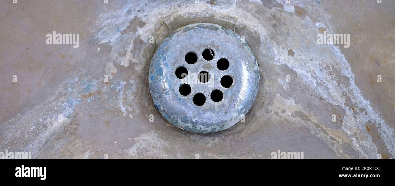 Old worn drain in sink or tub with mineral deposits and stains around ...