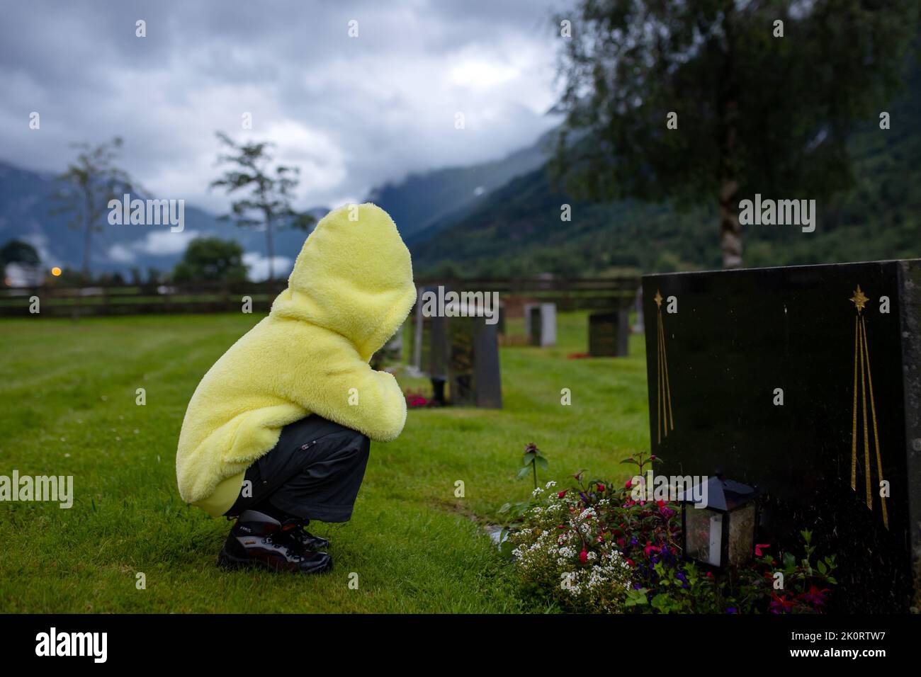 Sad little child, blond boy, standing in the rain on cemetery, sad ...