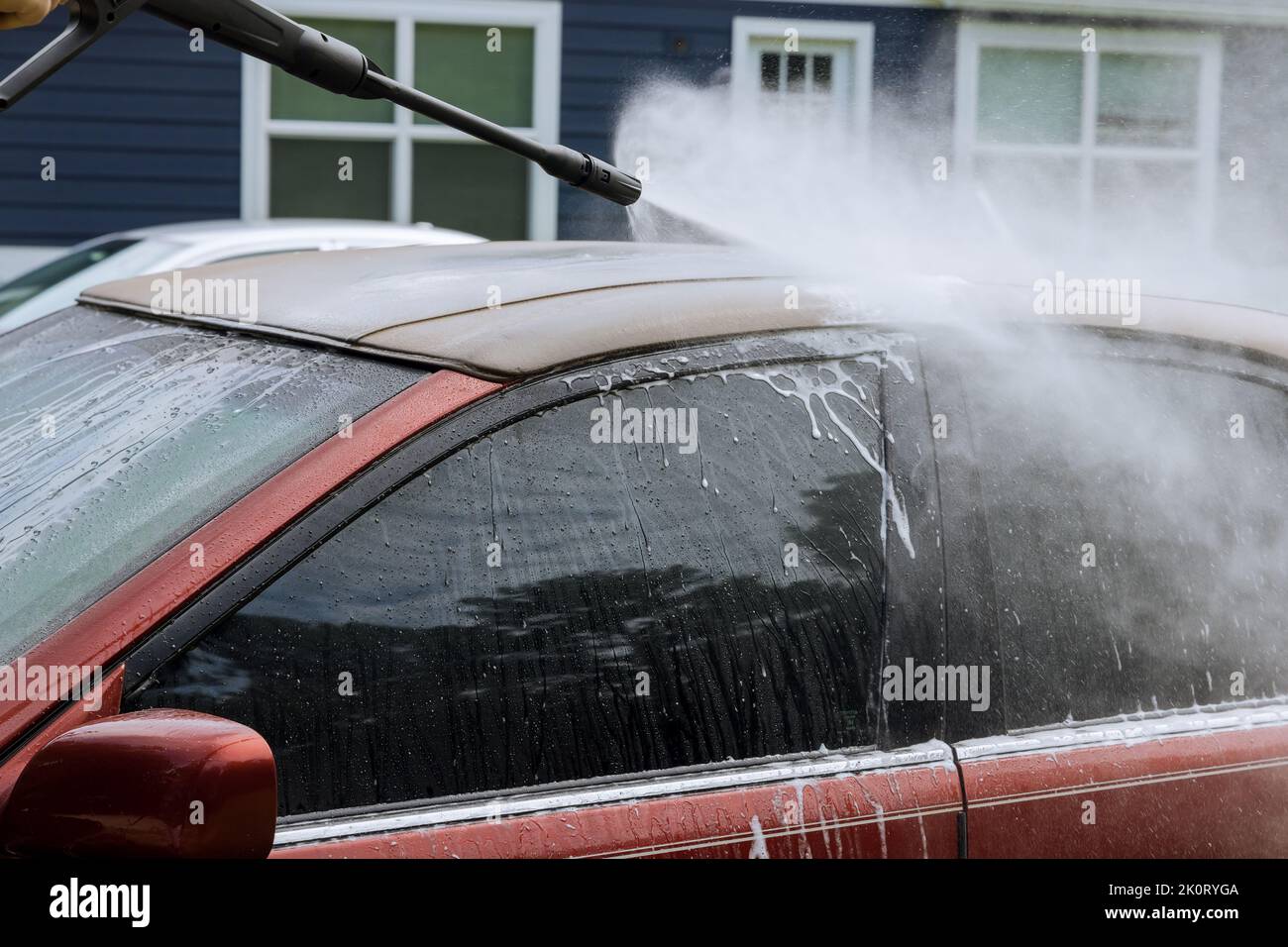 An a man washing a car using high pressure water jets while cleaning ...