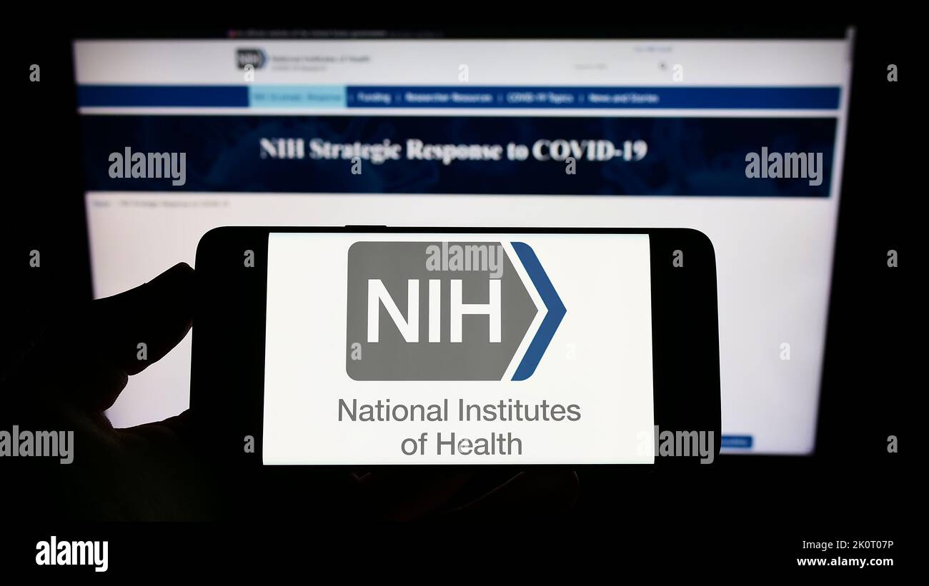 Person holding smartphone with logo of US agency National Institutes of ...